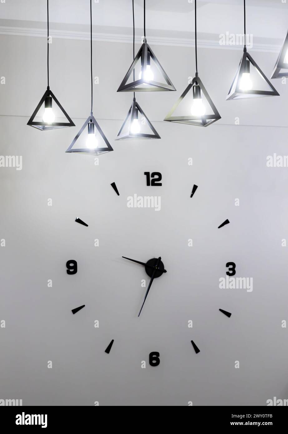 Minimalistic design of a wall clock with black numbers and a light bulb ...