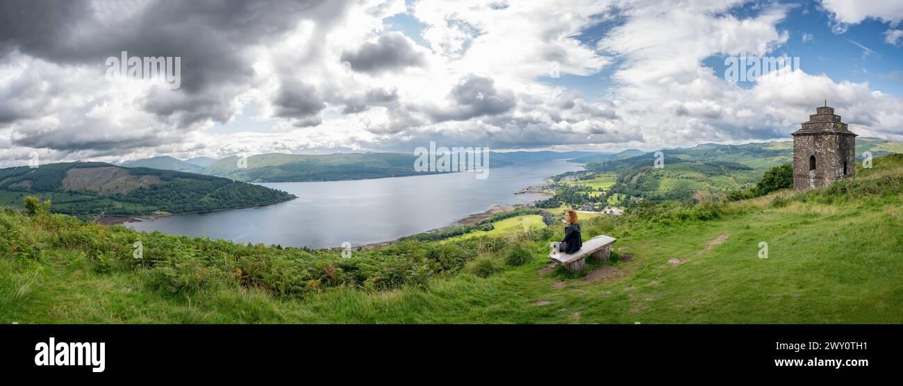 A woman, hiker restiong edge cliff watching Inveraray Castle, bay ...