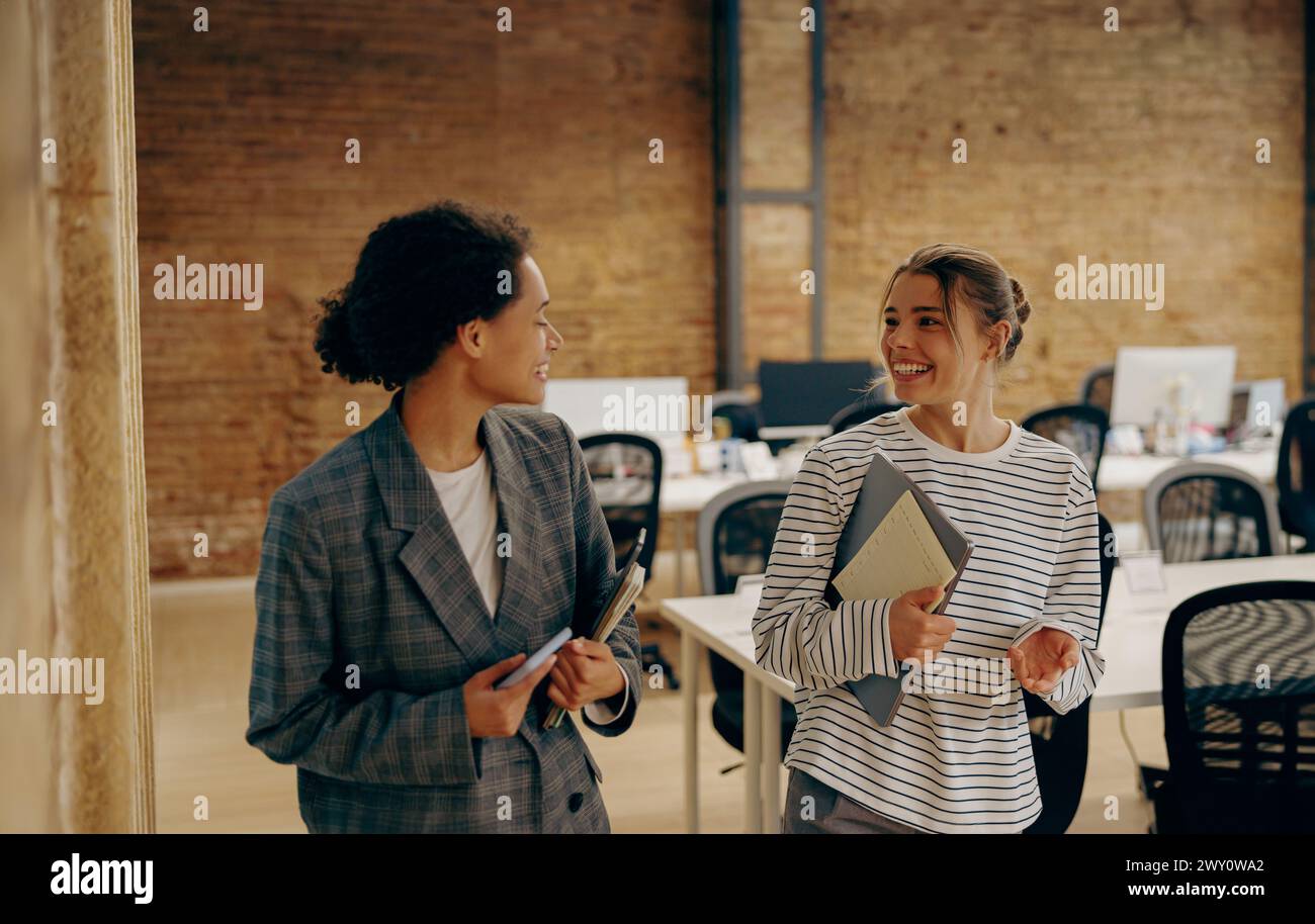Two female managers met in the office interior and stopped to talking ...