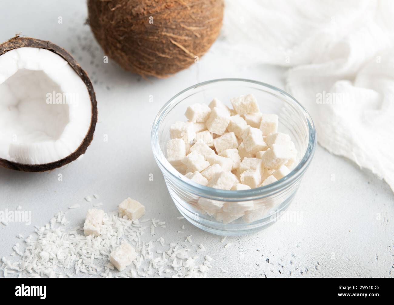 Dried coconut bites made from shredded flakes in glass bowl on light ...