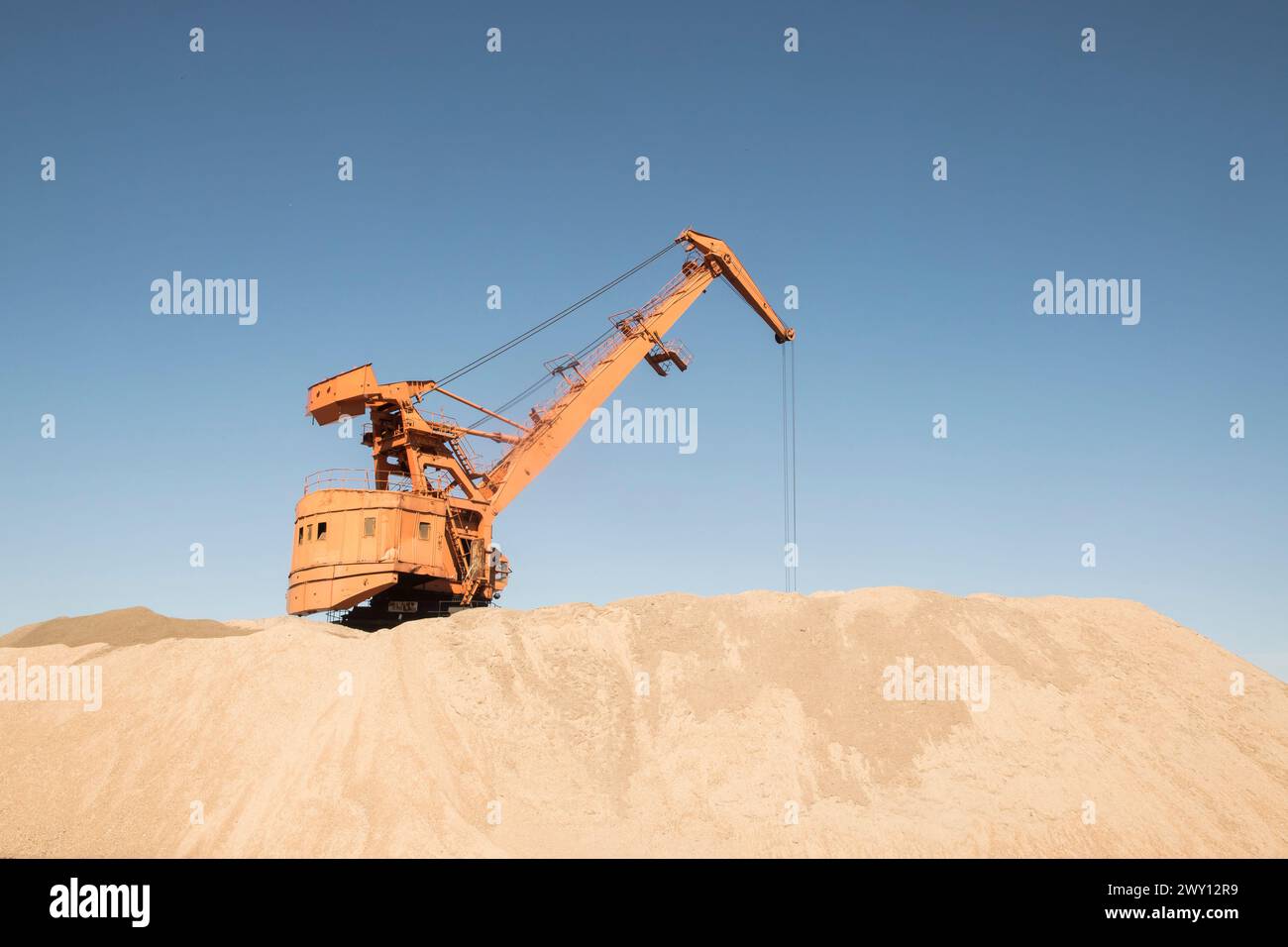 Port industrial cranes at river sand unloading depot on clear sunny day ...