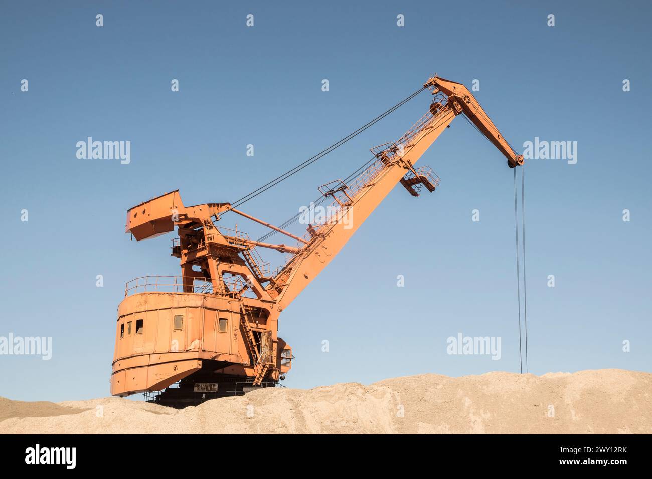 Port industrial cranes at river sand unloading depot on clear sunny day ...