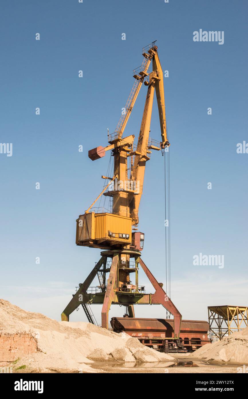 Port industrial cranes at river sand unloading depot on clear sunny day ...