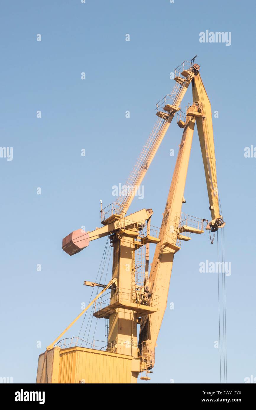 Port industrial cranes at river sand unloading depot on clear sunny day ...