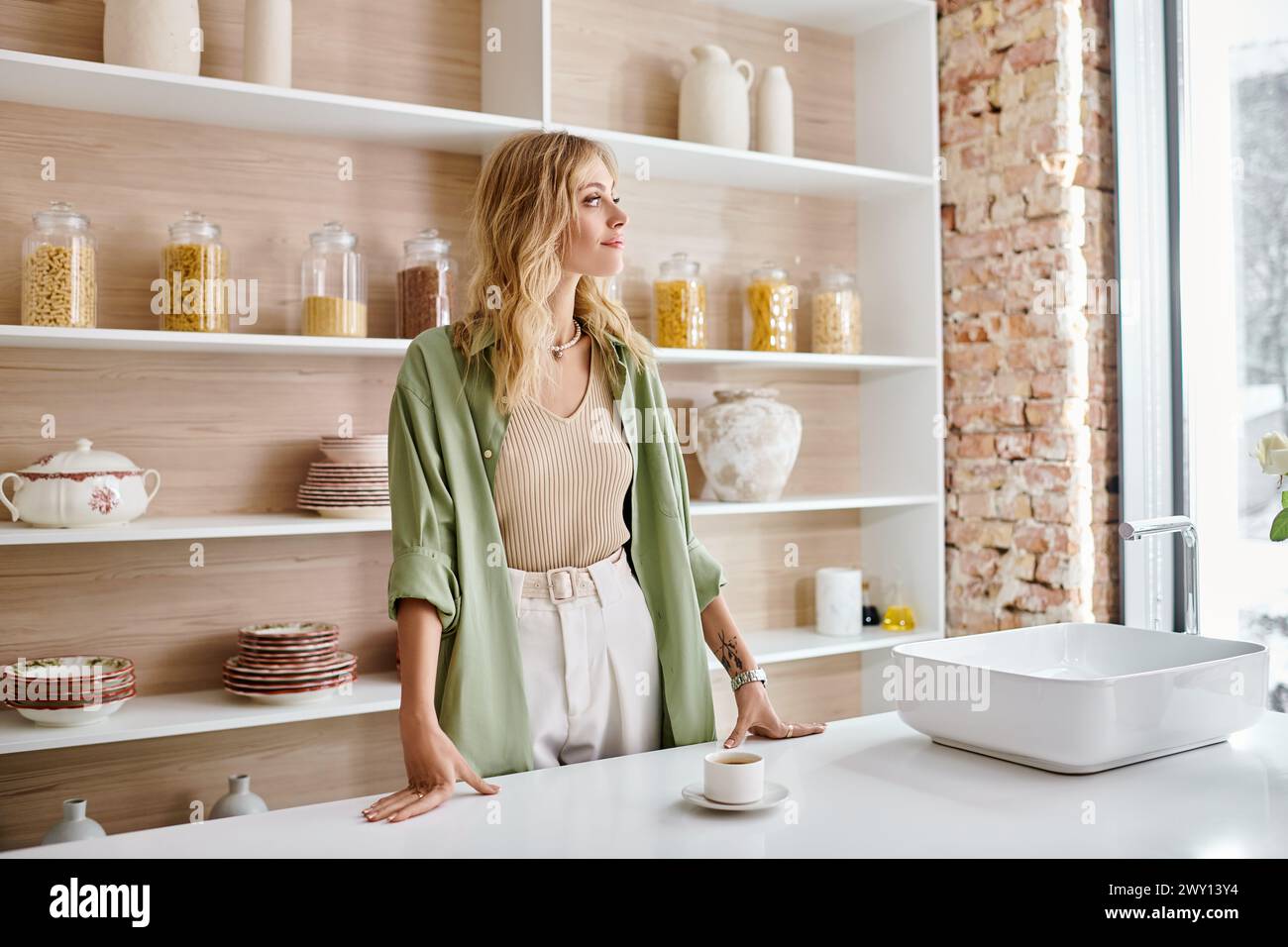 Woman in a kitchen looking out the window Stock Photo - Alamy