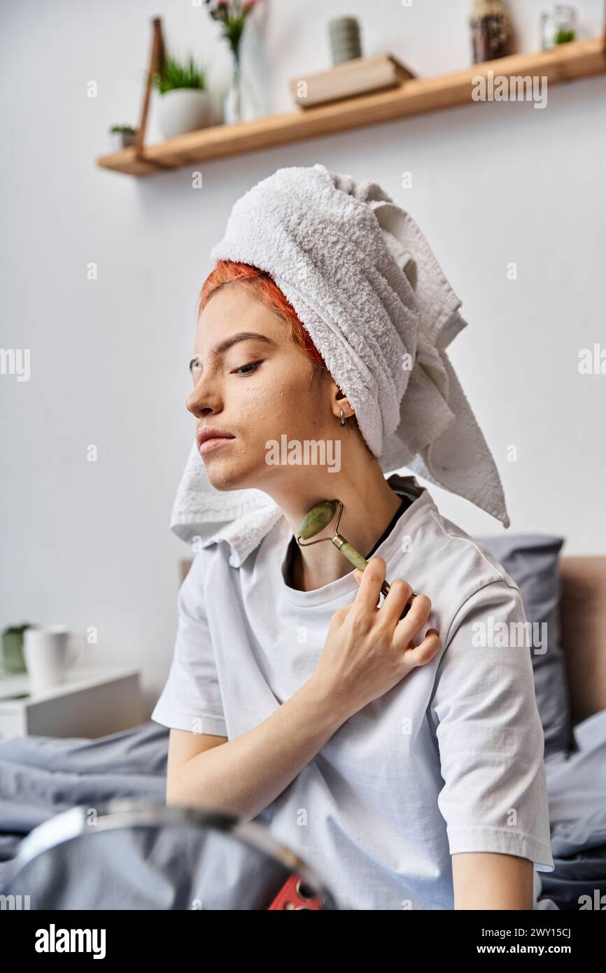 good looking queer person in cozy homewear using face roller in front ...