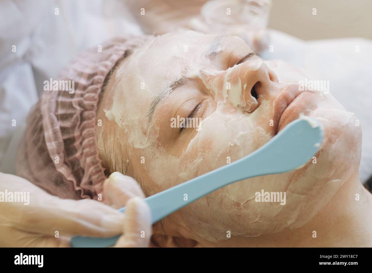 A woman is having a facial mask applied to her face in a spa setting ...