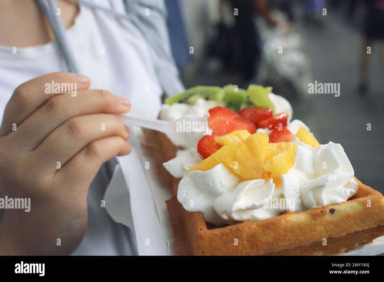A close-up view of a hand holding a delicious waffle topped with fresh ...