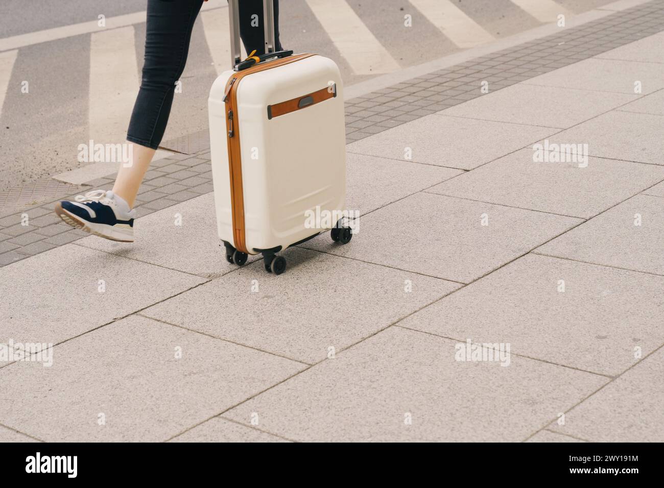 A woman is walking down a city sidewalk while pulling a piece of ...