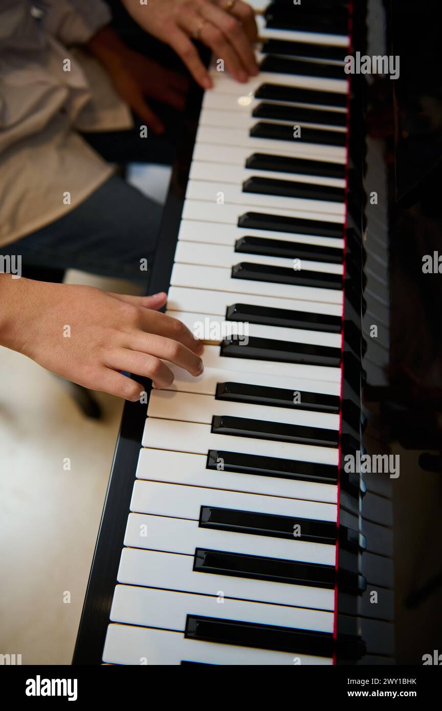 View from above of the hands of a pianist musician kid playing piano ...