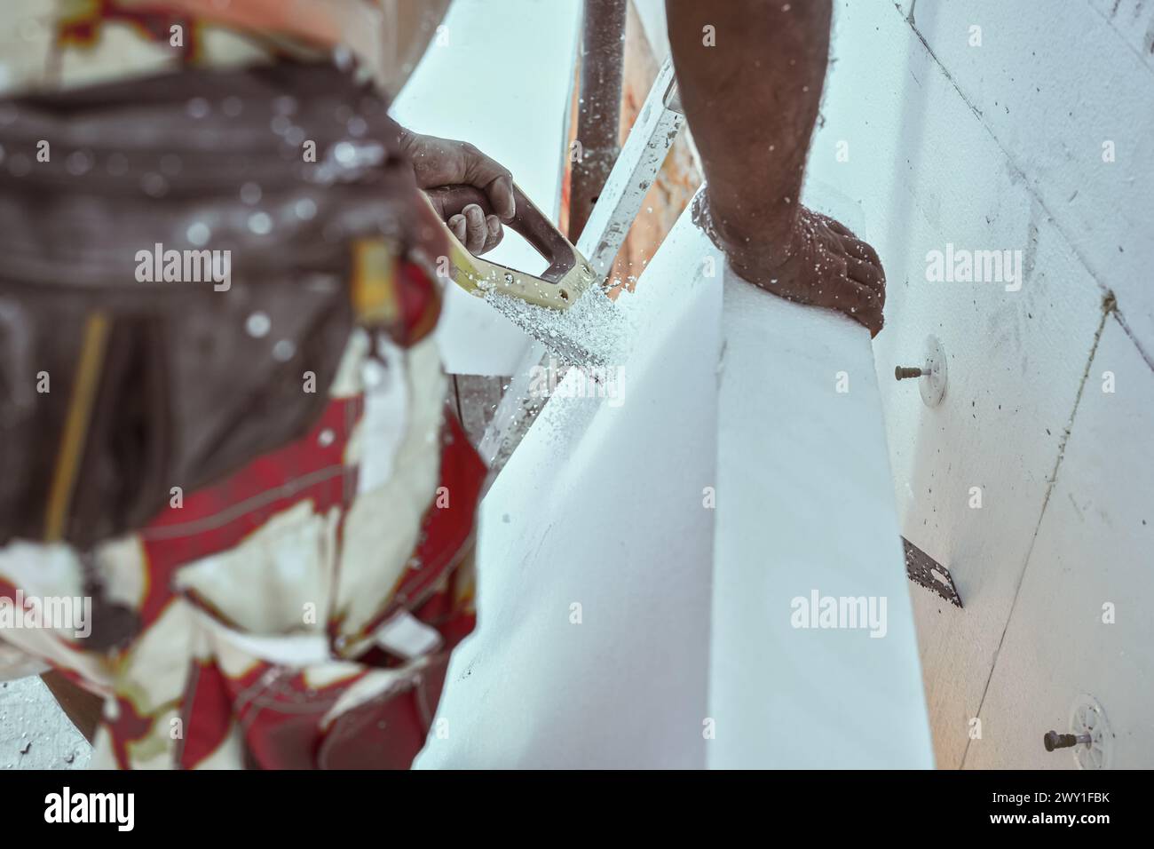 Man construction worker cutting polystyrene foam heat insulation with ...