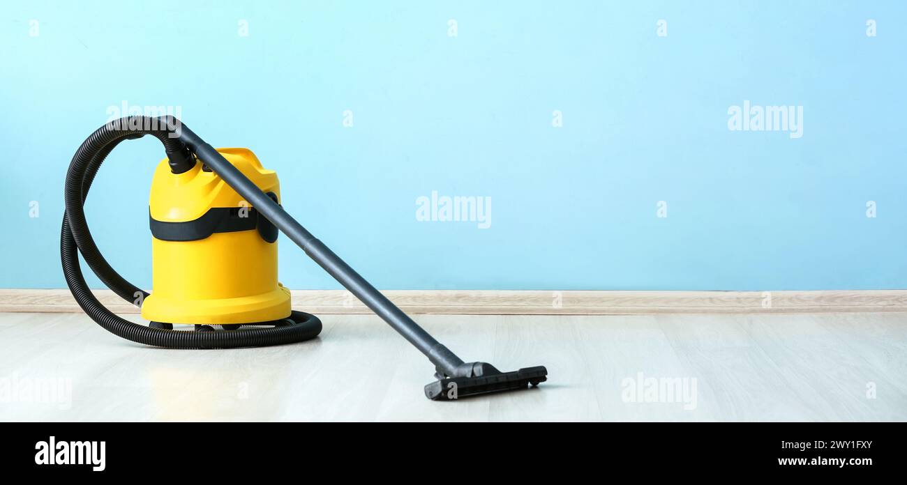 Modern vacuum cleaner near blue wall in room. Banner for design Stock ...