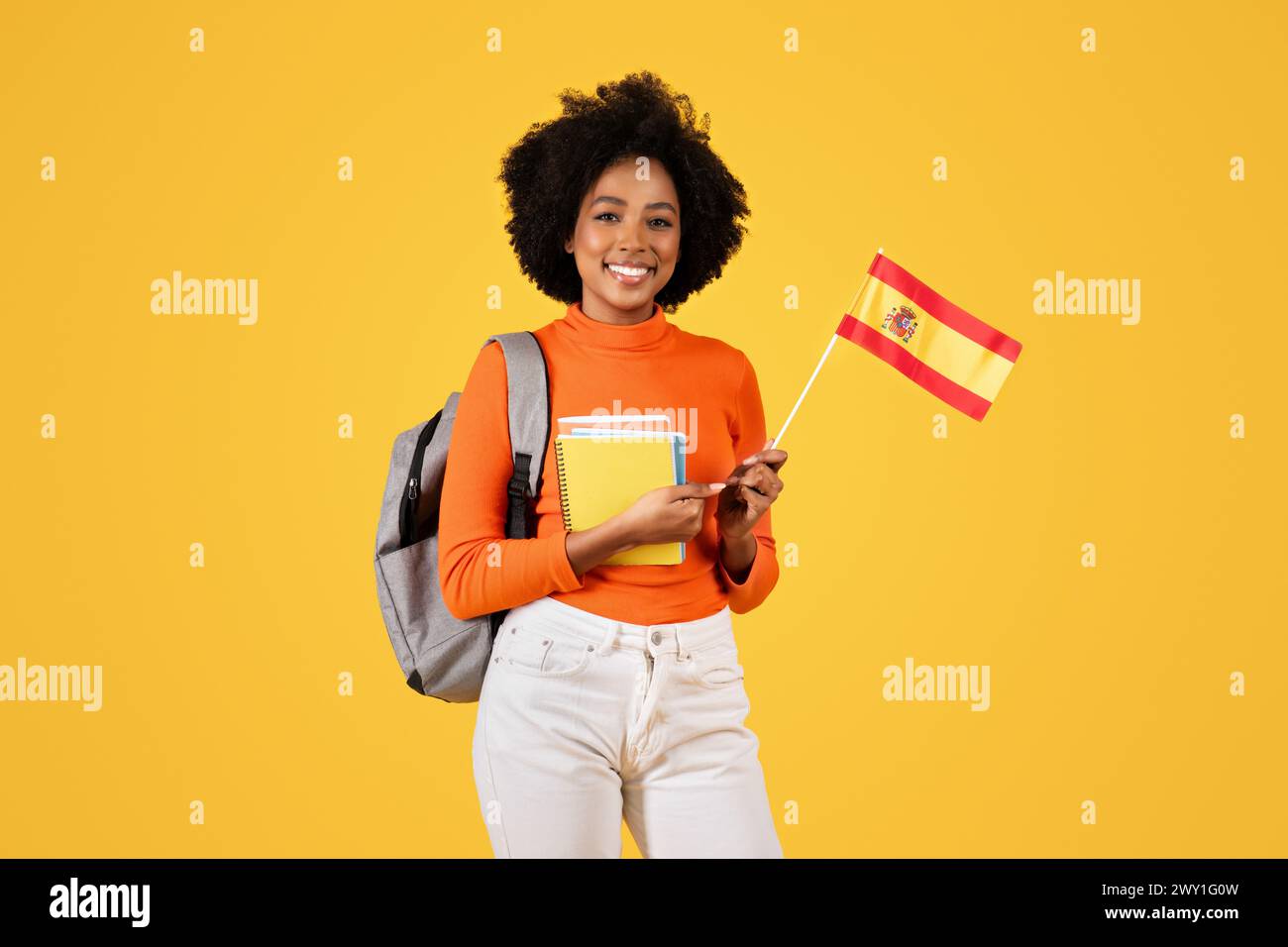 Cheerful African American female student proudly holding a Spanish flag ...