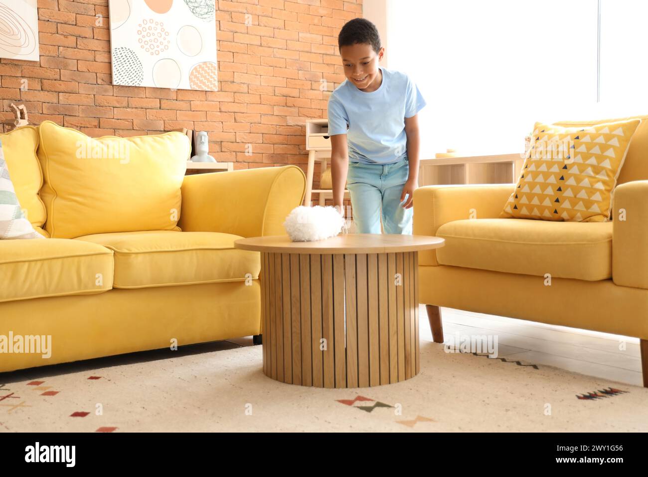 Cute little African-American boy cleaning table with duster in living room Stock Photo - Alamy