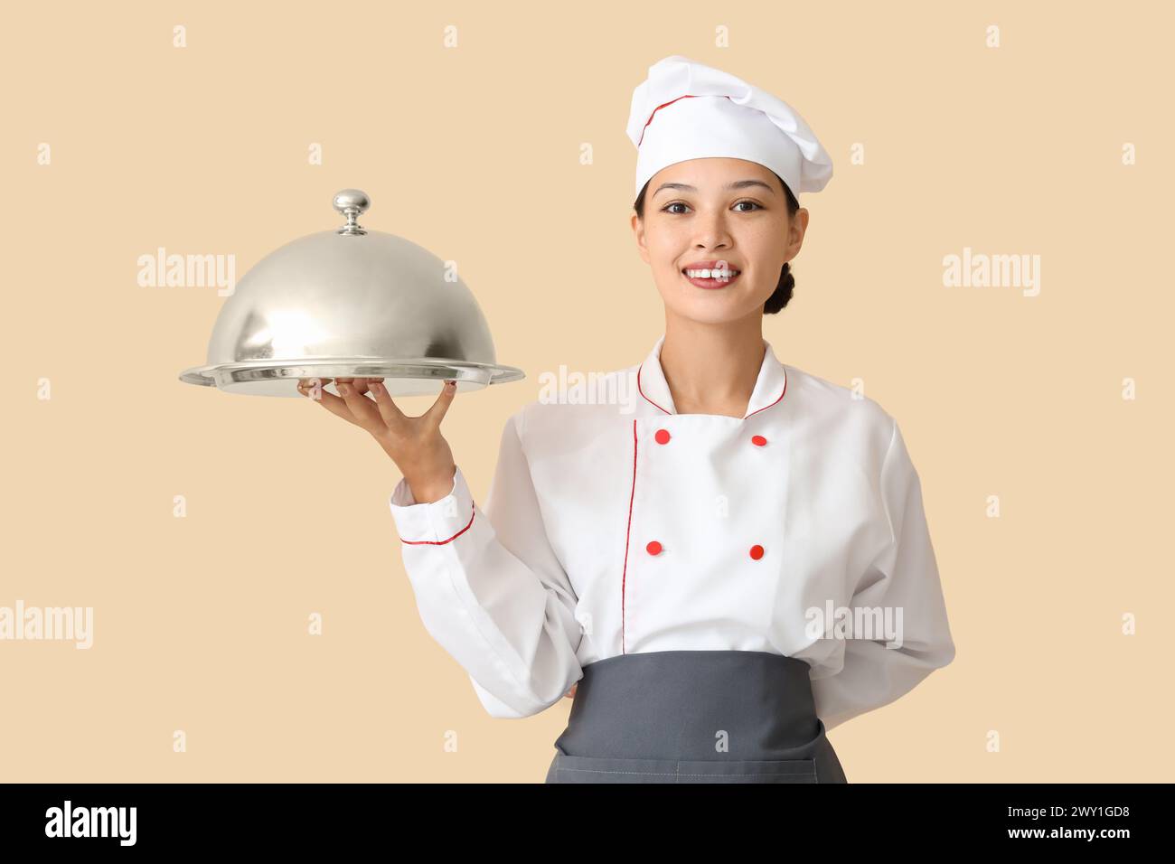 Female Asian chef with cloche on beige background Stock Photo - Alamy