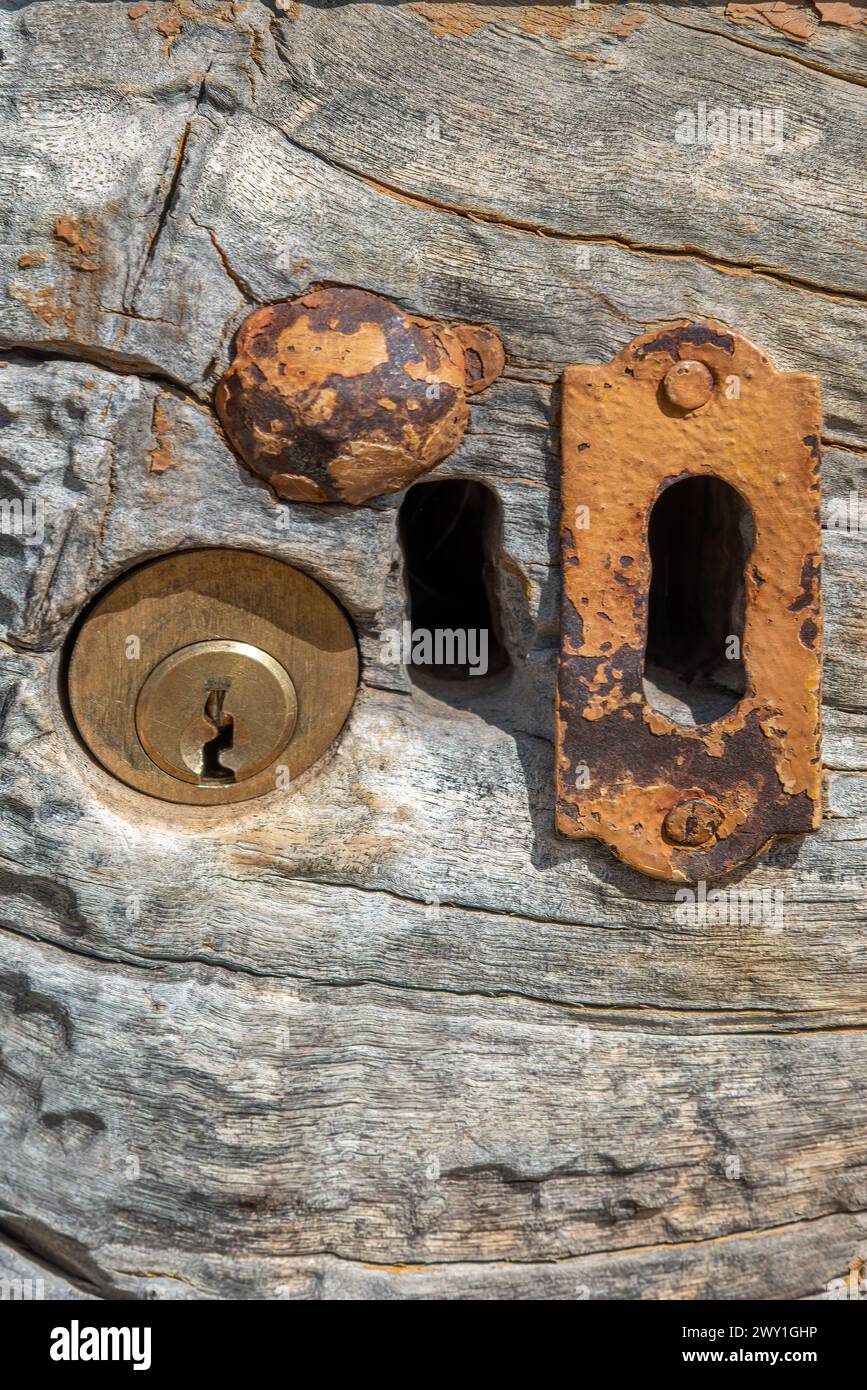 Close-up of rusty antique keyhole next to modern lock on weather-worn ...