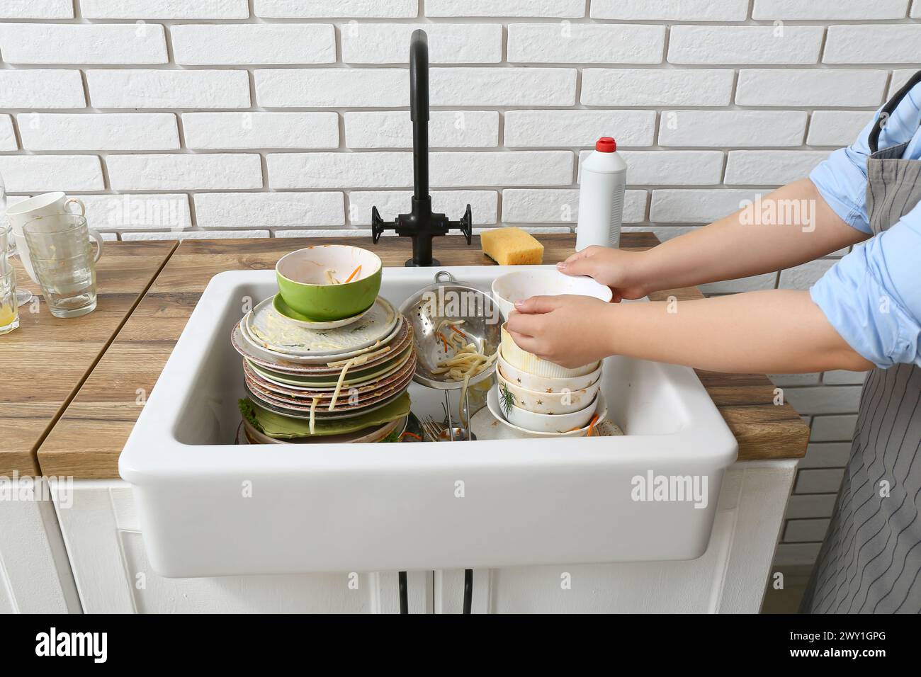 Woman washing dirty dishes in sink near white brick wall Stock Photo ...