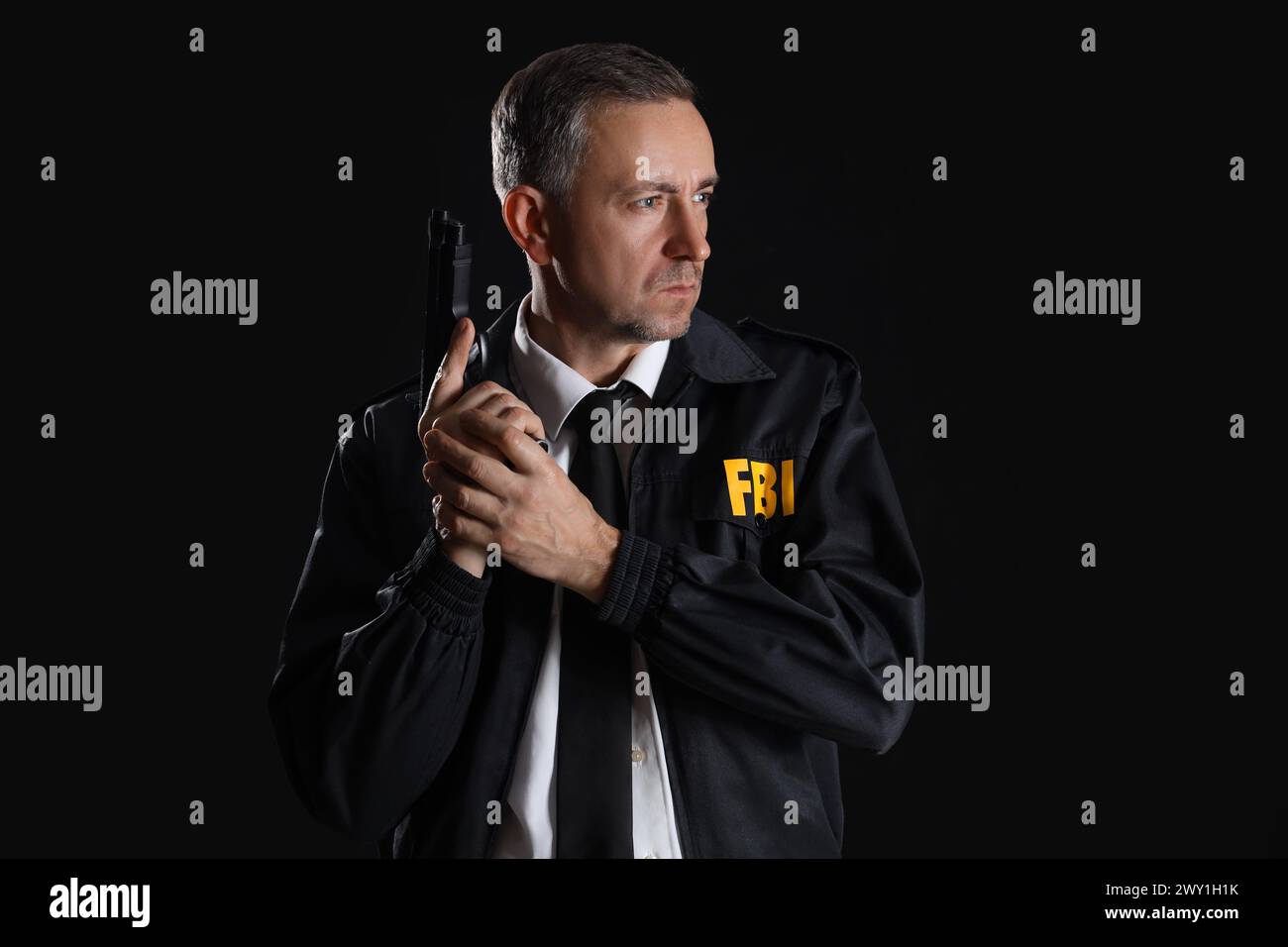 Mature FBI agent with gun on black background Stock Photo - Alamy
