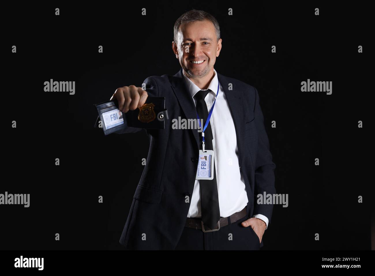 Mature FBI agent showing document on black background Stock Photo - Alamy