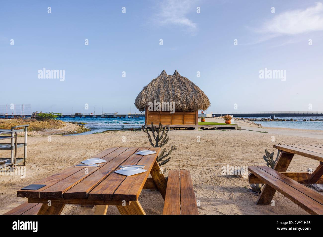 View of seaside restaurant featuring wooden tables outdoors with ...