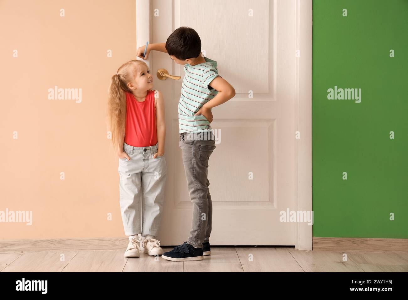 Cute little kids measuring height near door at home Stock Photo - Alamy