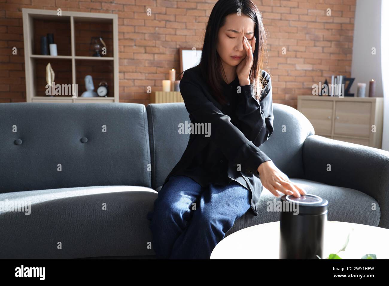 Grieving young Asian woman with mortuary urn at funeral Stock Photo - Alamy