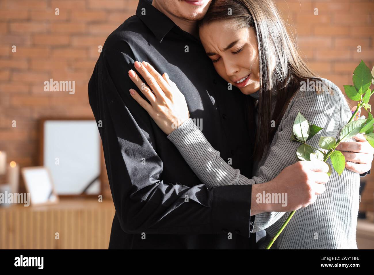 Mourning young couple with rose hugging at funeral Stock Photo - Alamy