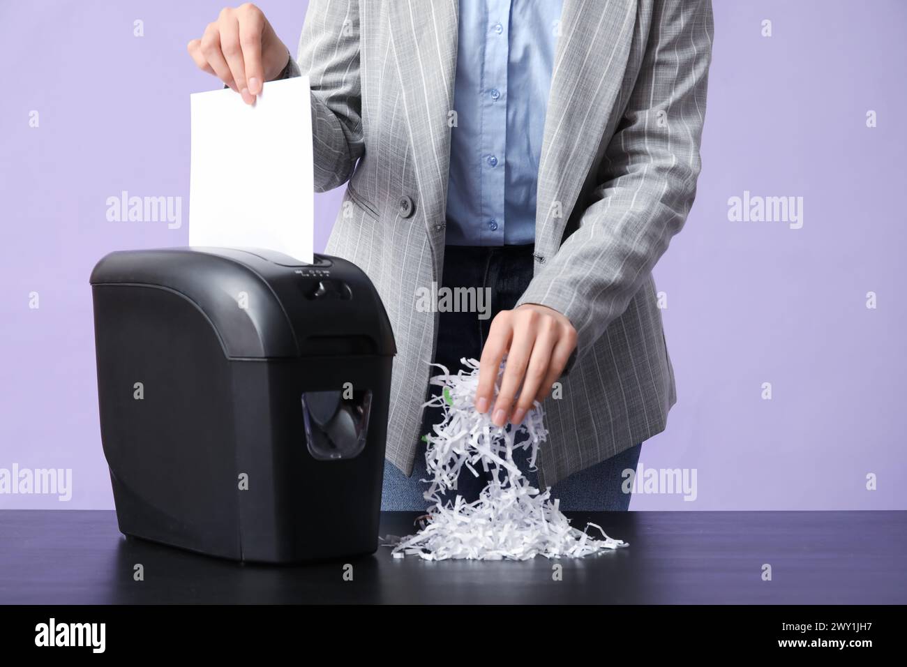 Secretary destroying document in shredder on lilac background Stock ...