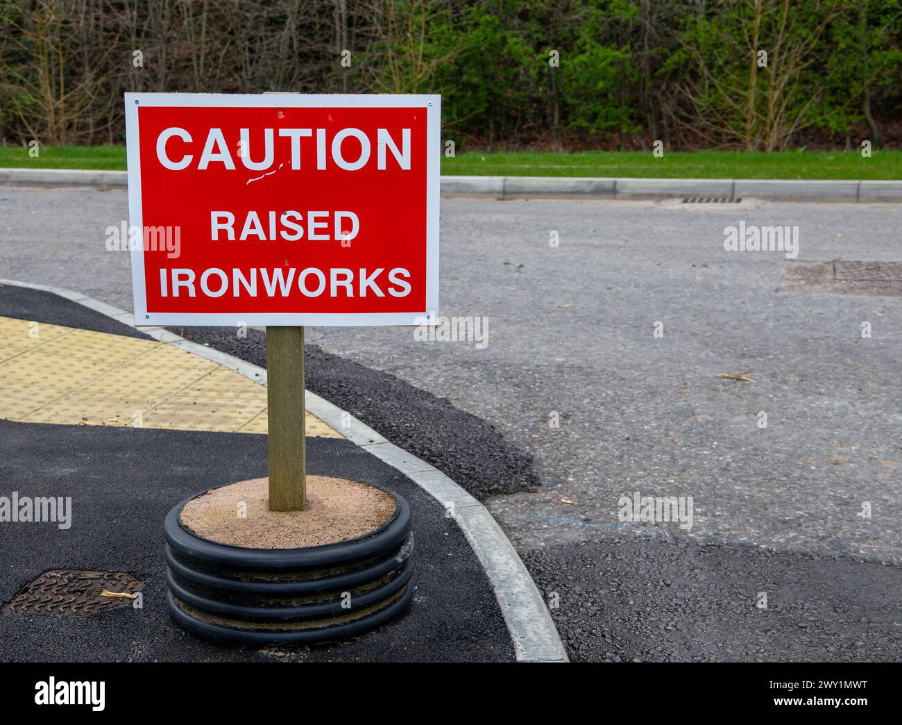 Caution raised ironworks road sign on the pavement sidewalk at recently ...