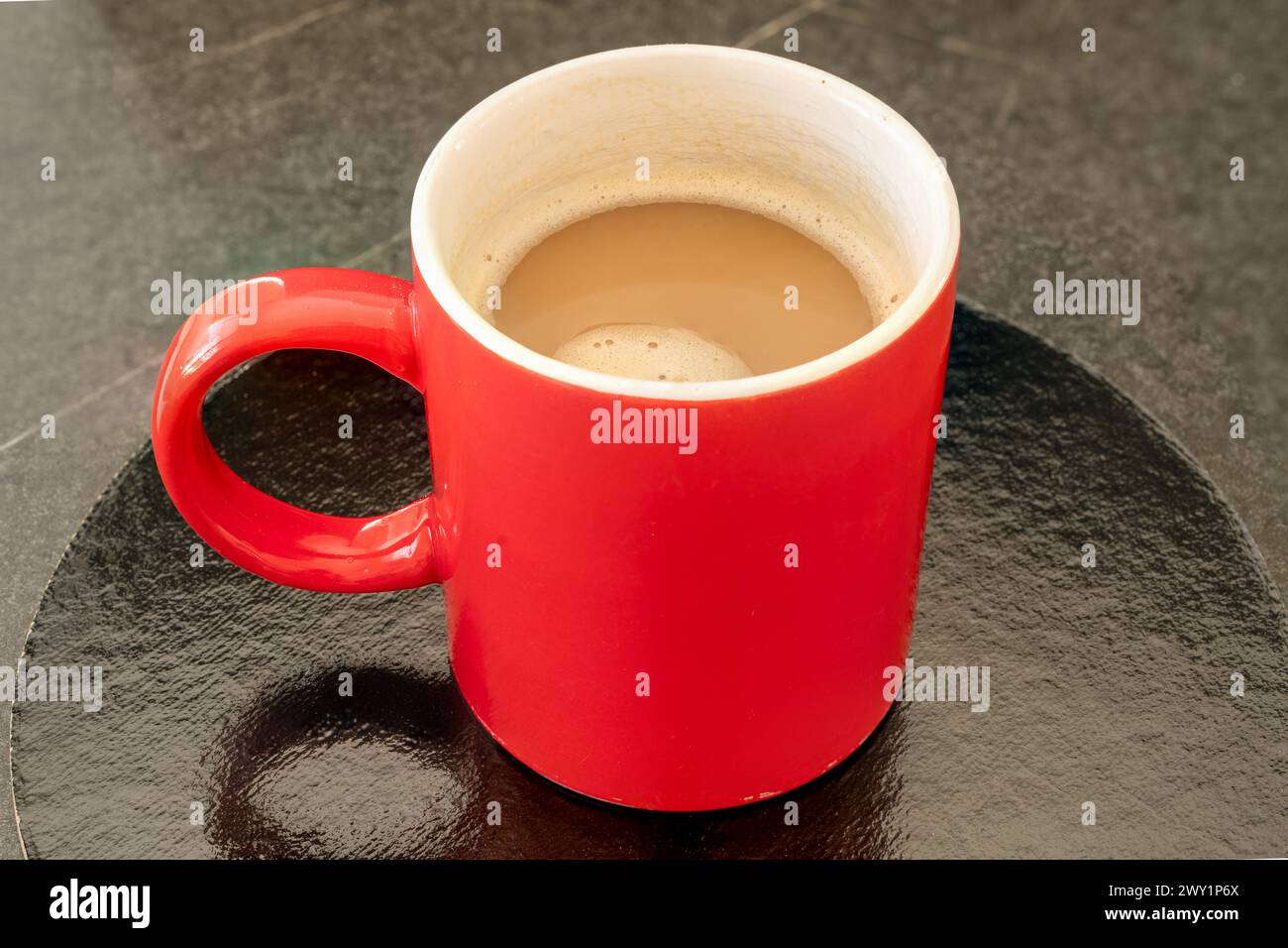 Red cup of coffee on a black reflective coaster and dark table. Coffee ...