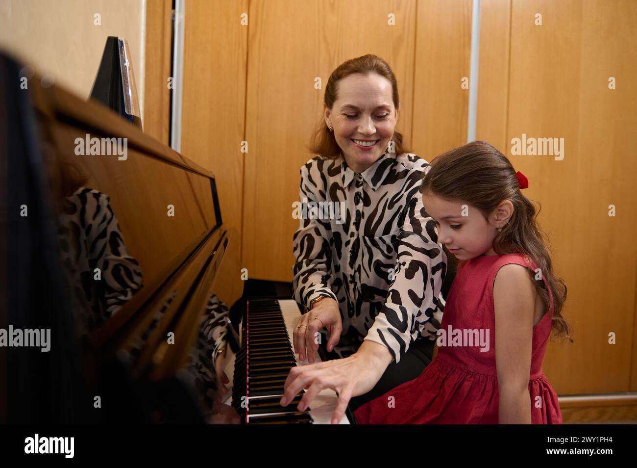 Cheerful beautiful woman pianist, musician teacher smiling while ...