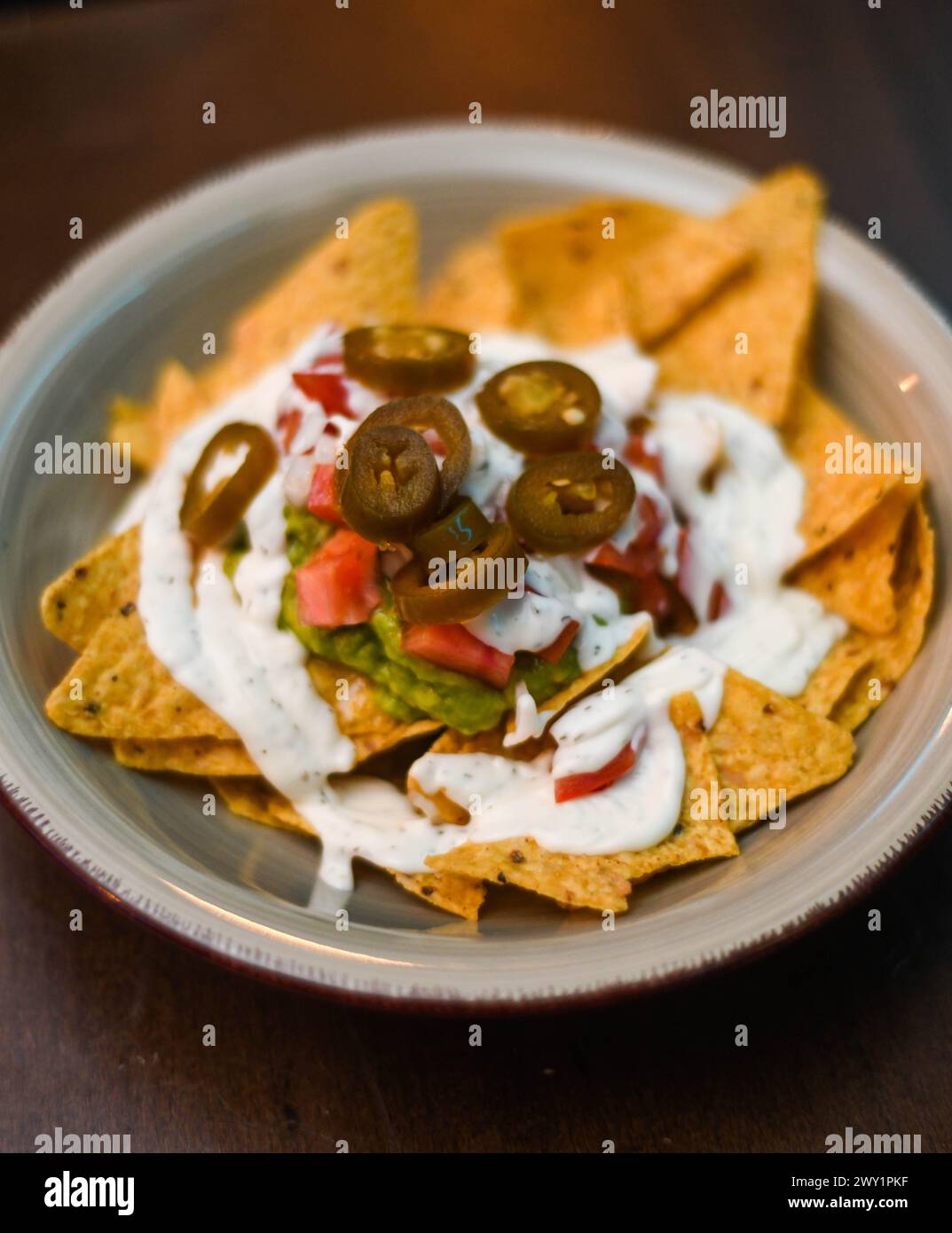 Serving of nachos with white sauce and jalapenos Stock Photo - Alamy