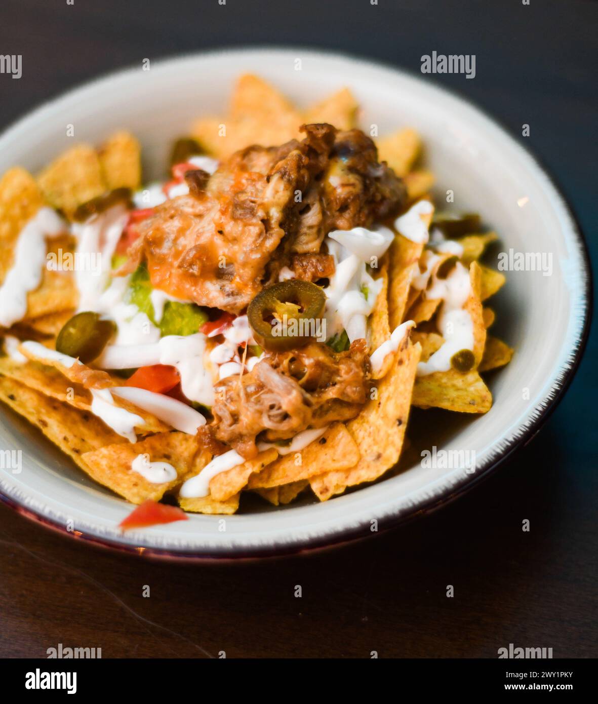 Serving of nachos with meat, cheese, white sauce and jalapenos Stock ...