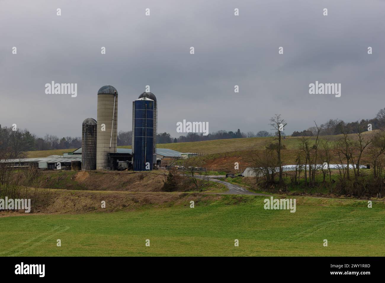 Agricultural landscape with barn and silos on a hillside under cloudy ...