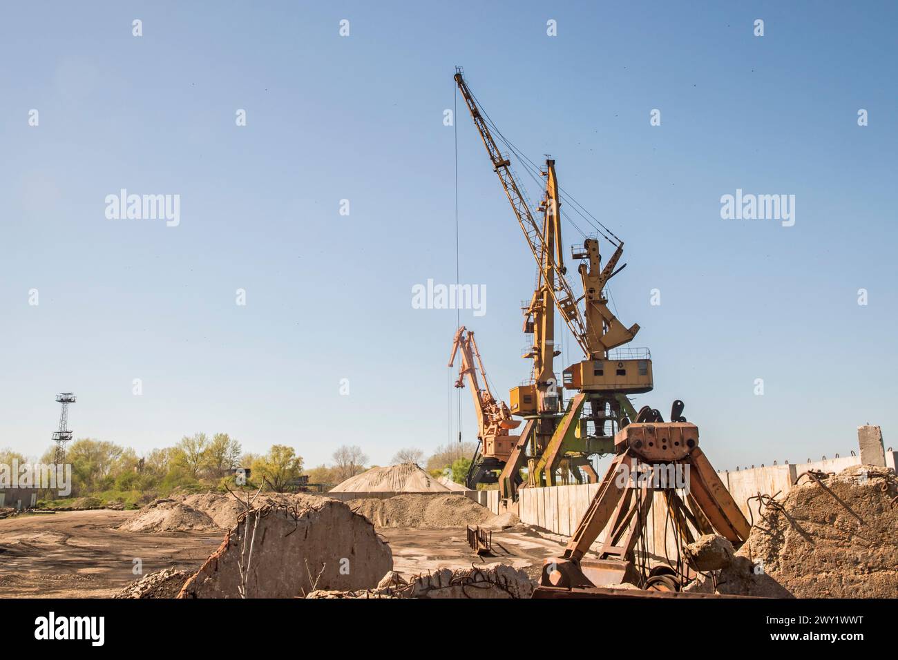 Port industrial cranes at river sand unloading depot on clear sunny day ...