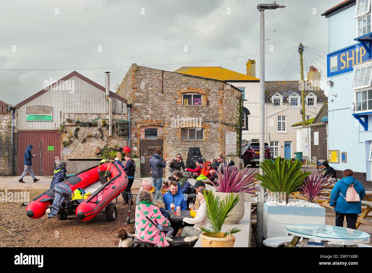 Three men pulling dinghy up the river Teign beach at Teignmouth, Devon ...