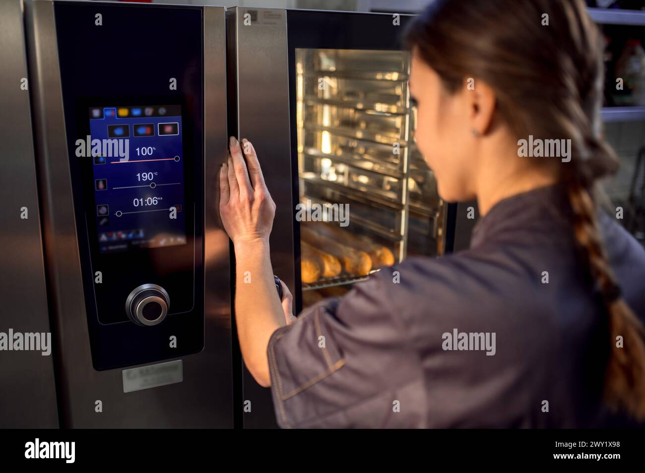 Woman baker using electrical oven for baking French baguettes Stock ...
