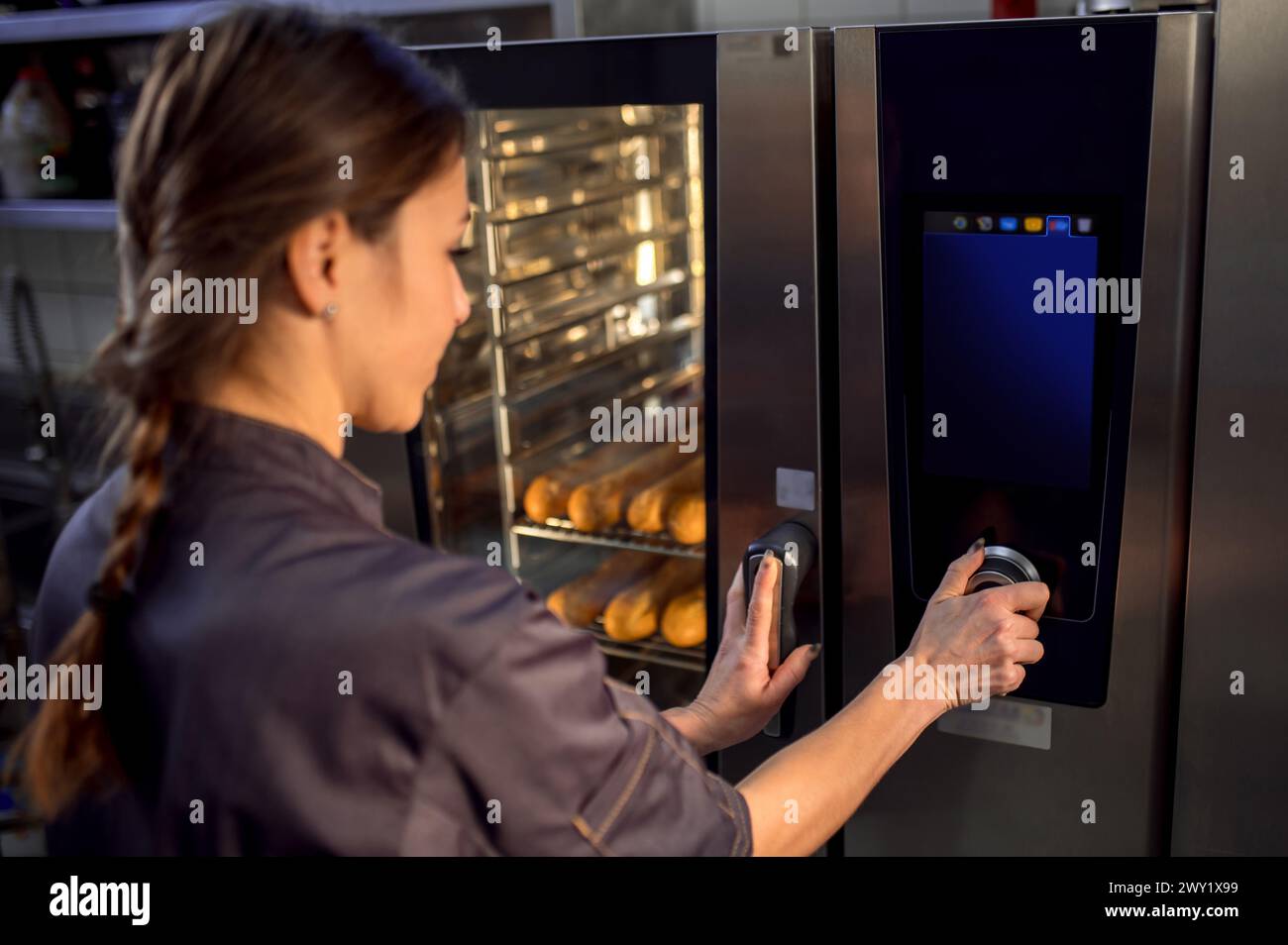 Woman baker using electrical oven for baking French baguettes Stock ...
