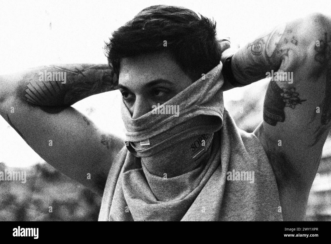 Concealed behind his hands, a young man shields his face, veiling his ...