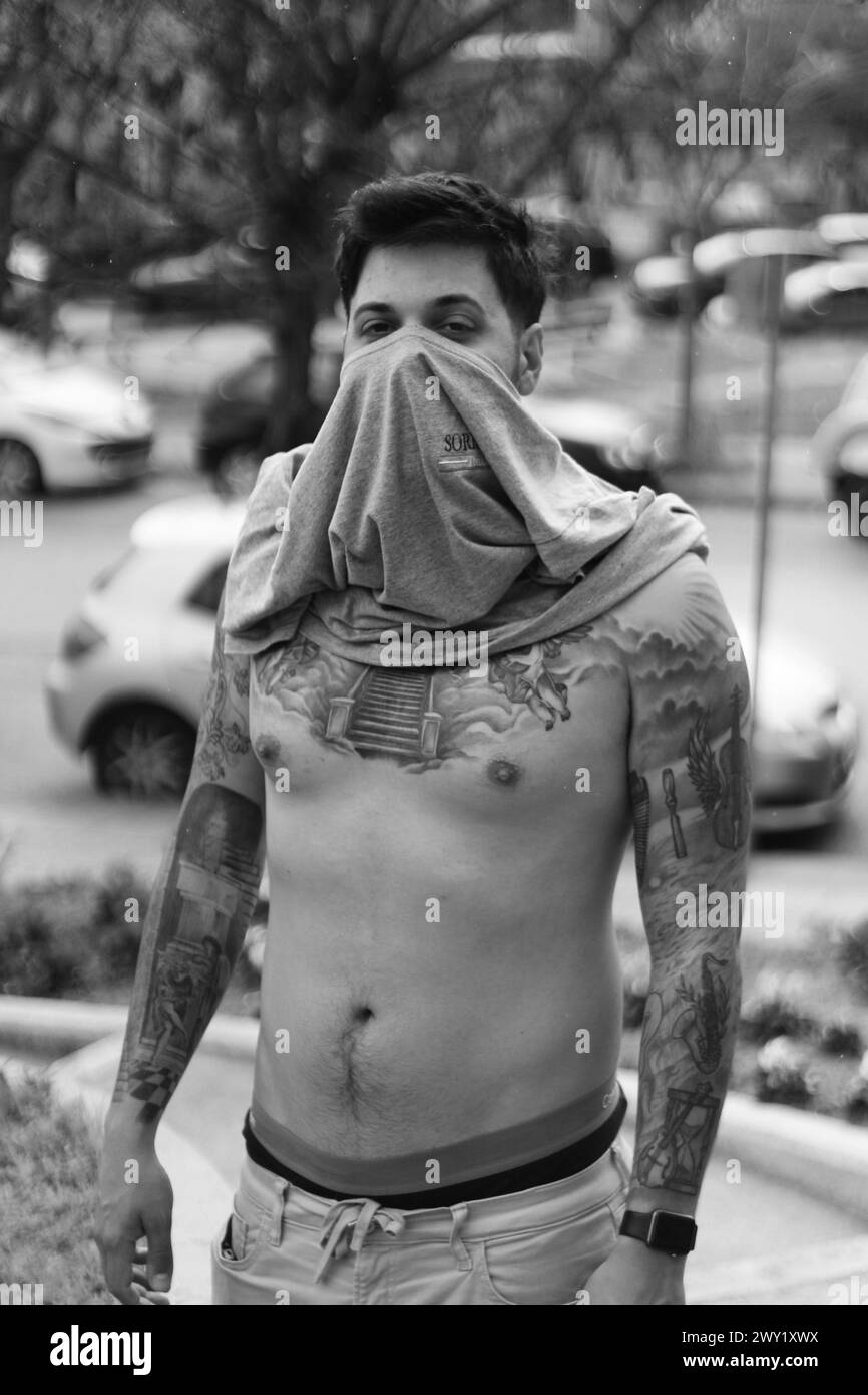 Concealed behind his hands, a young man shields his face, veiling his ...