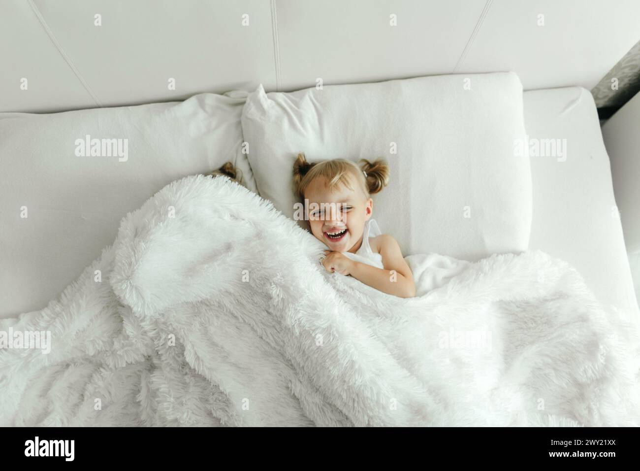Two young female children are resting comfortably in a bed covered in ...