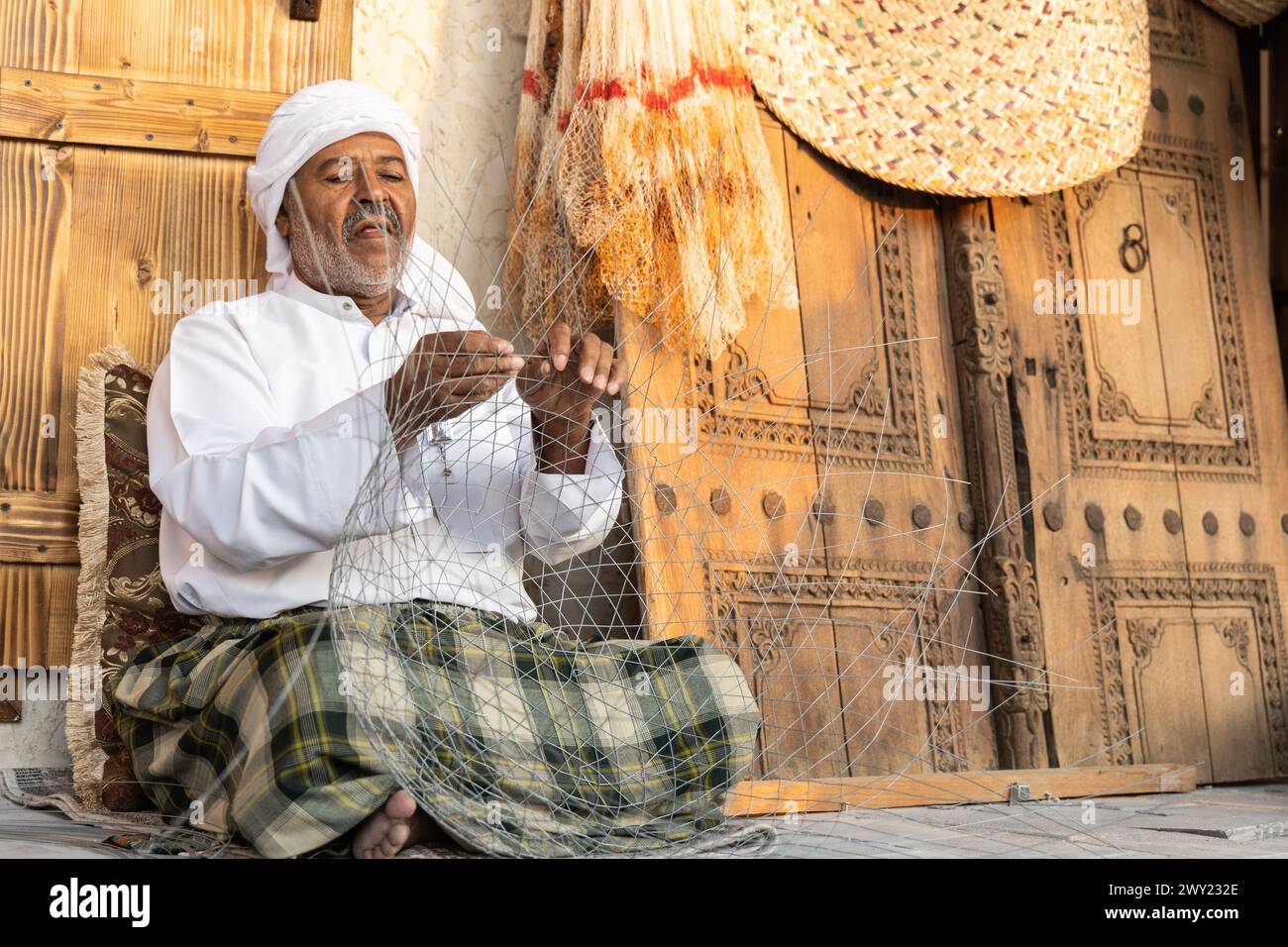 The old man is weaving a traditional metal fishing cage in Darb Al Saai ...