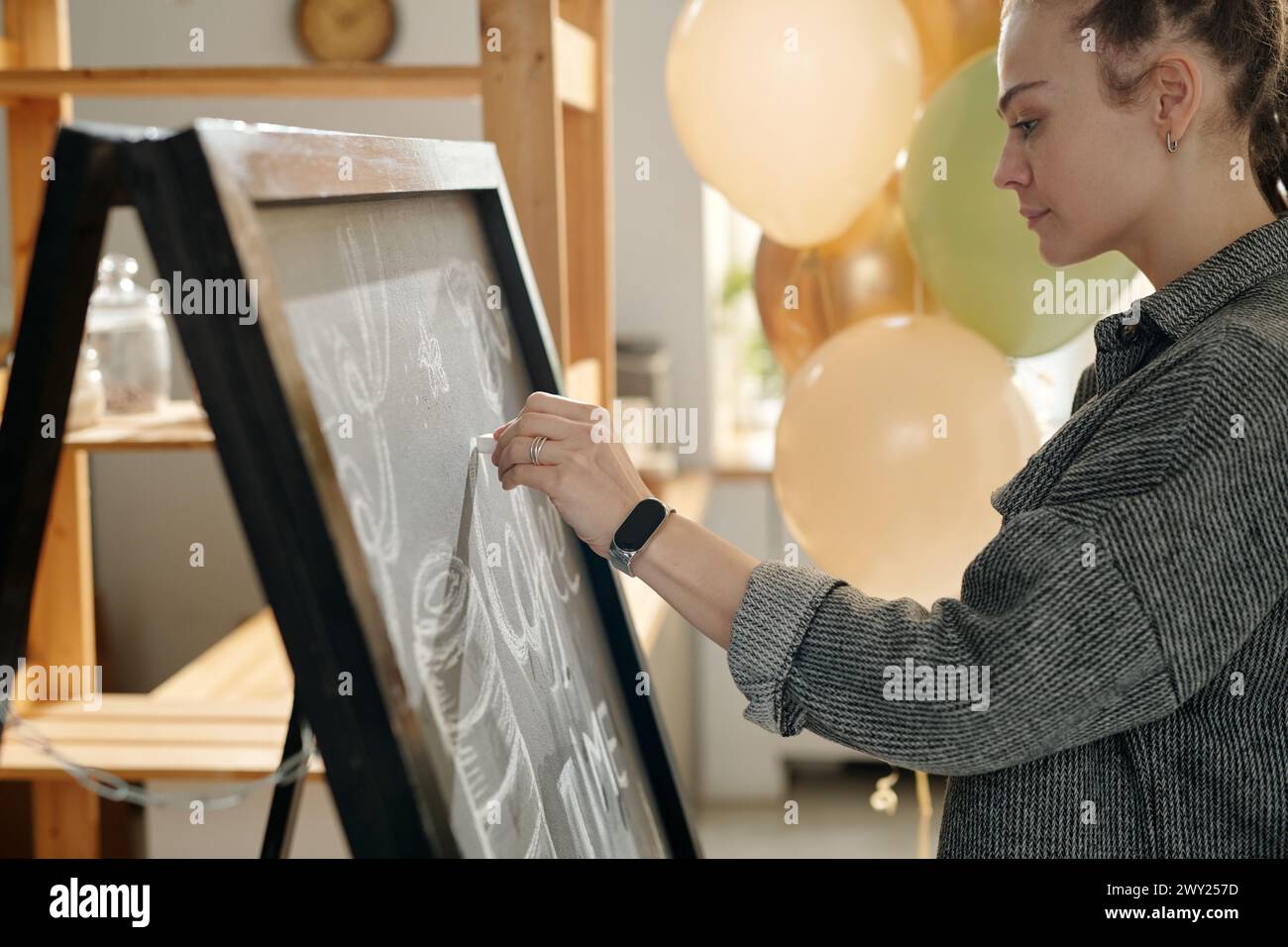 Side view of young businesswoman in grey shirt drawing advert with ...