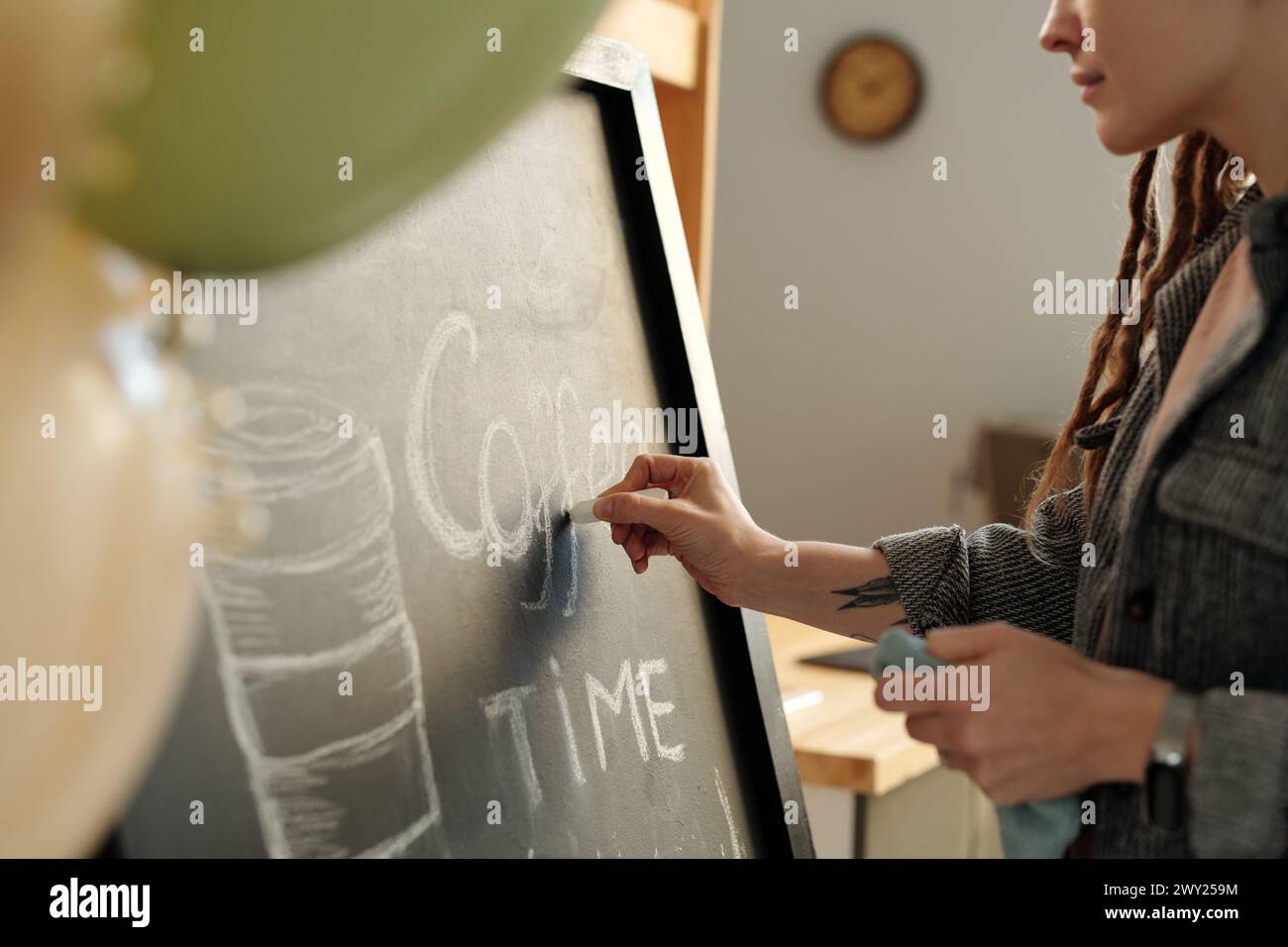 Hand of young female owner of cafe with piece of white chalk drawing ...