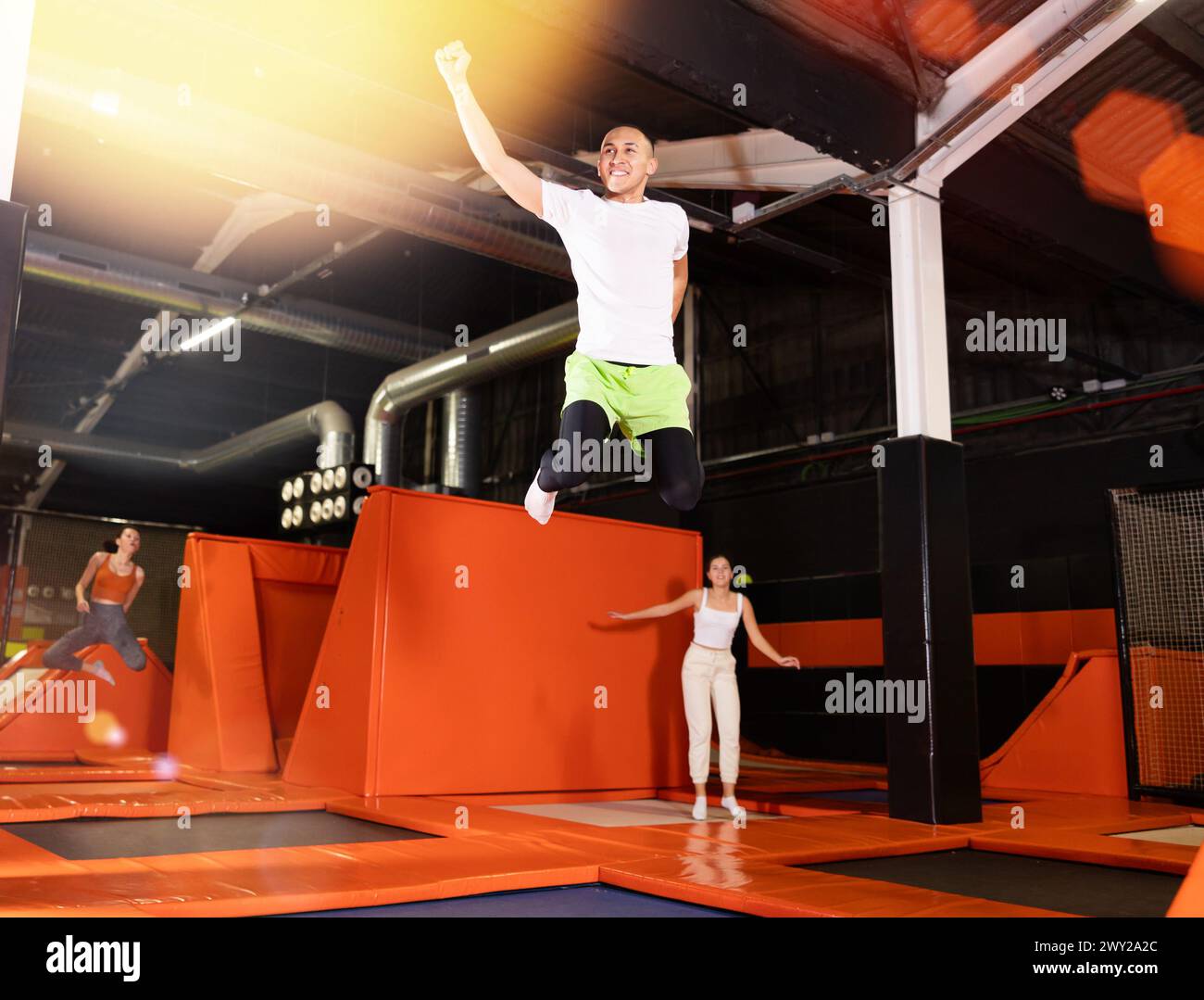 Joyful young man jumping on trampolines in colorful amusement park Stock Photo - Alamy