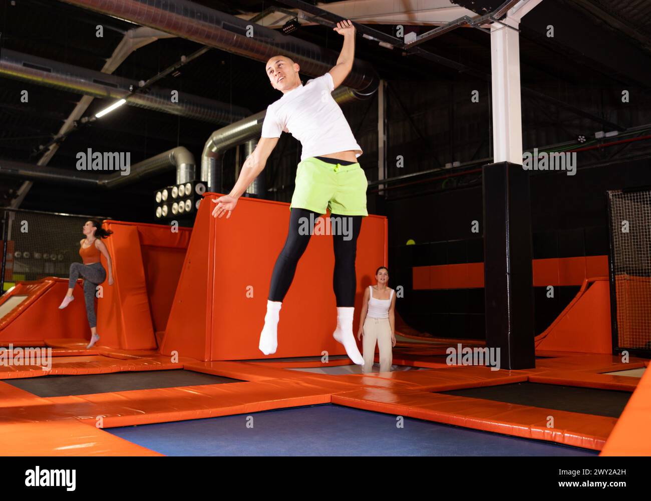 Emotional man jumping vertical and flying in trampoline sport center ...