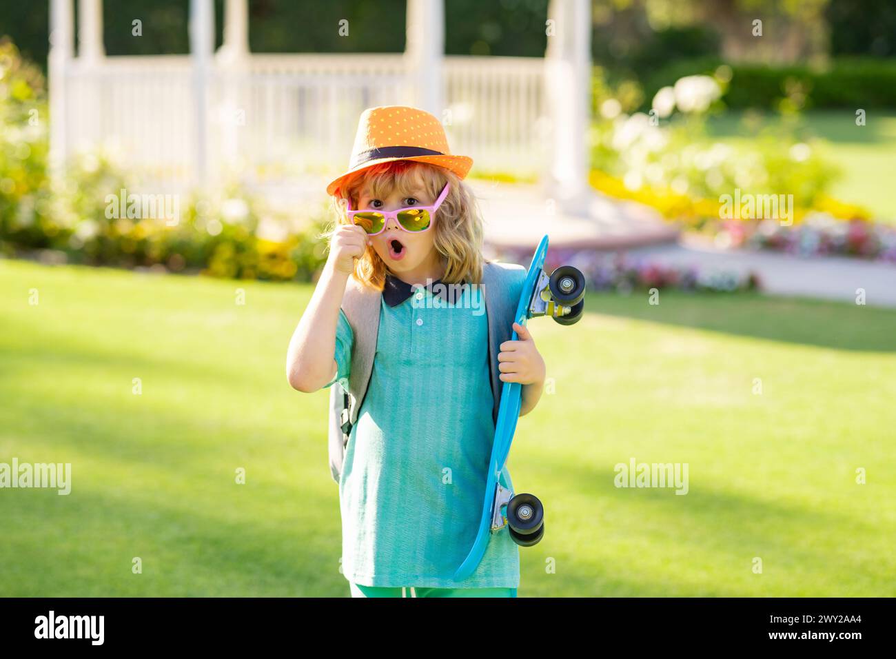 Childhood and fashion. Cute child with skateboard on summer park ...
