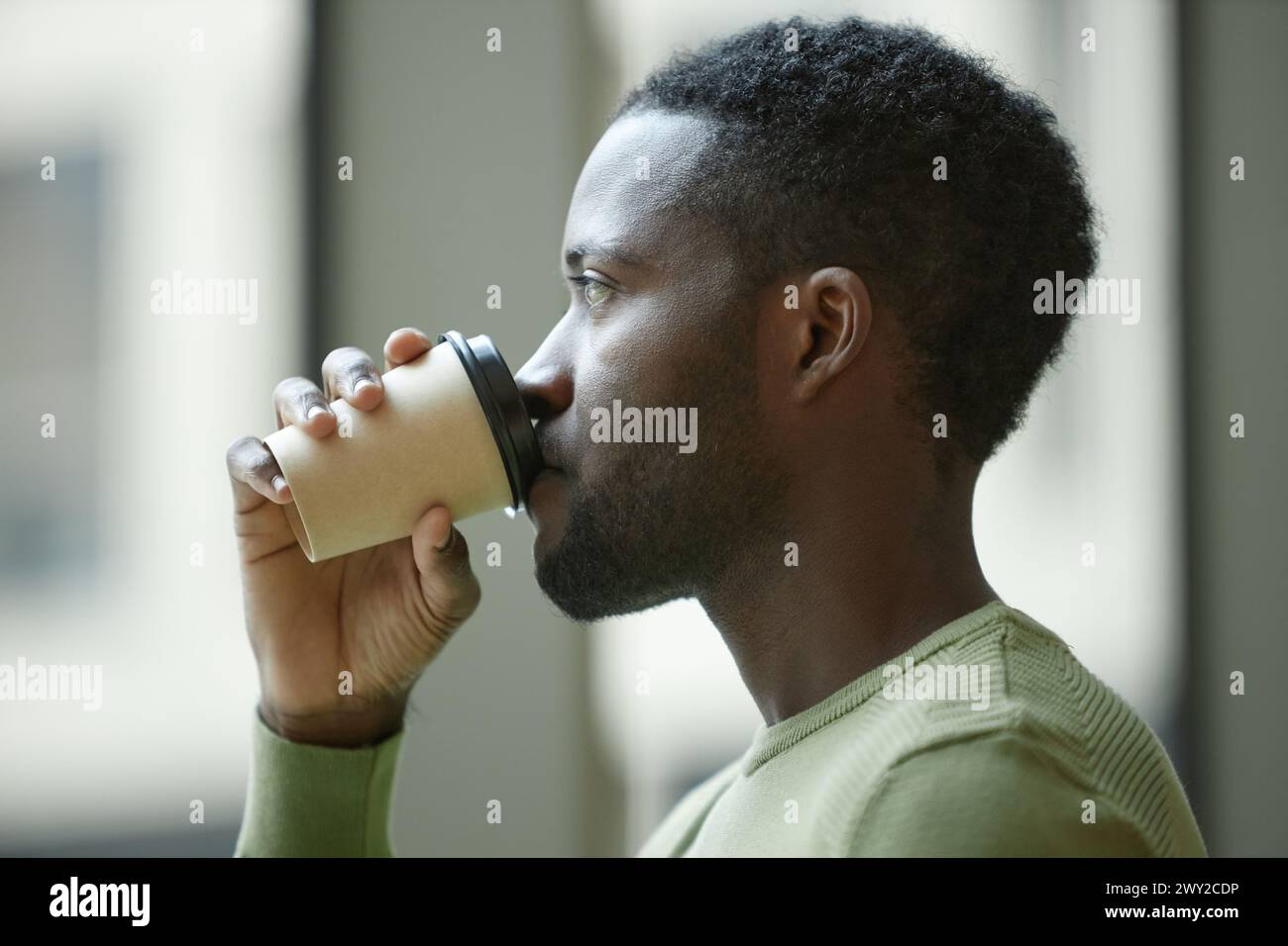 Side view closeup of Black man drinking coffee with paper cup against ...