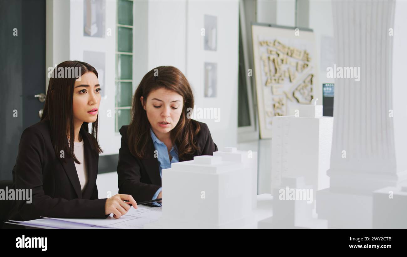 Architectural agency workers taking notes on blueprints, calculating ...