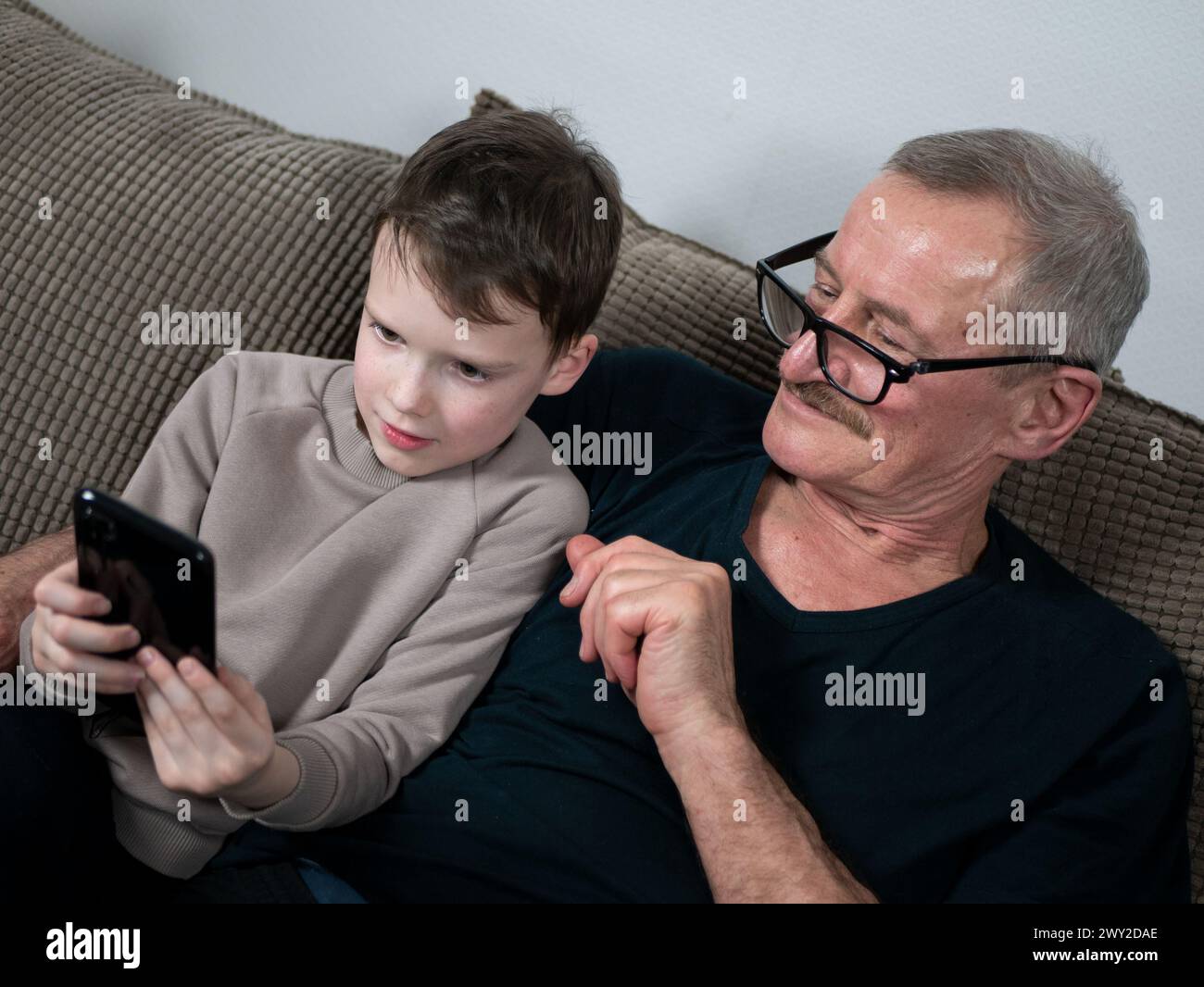 Grandfather and grandson staring at the smartphone with interest ...